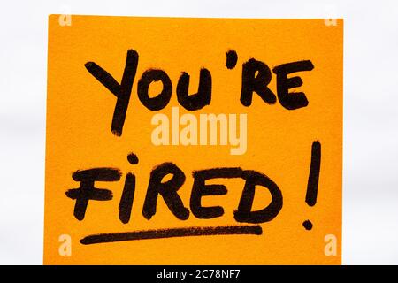 You're Fired text on orange sticky note on top of white keyboard. Human ...