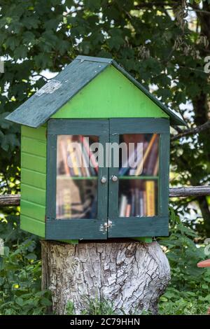 A small community book exchange box filled with books stands beside ...