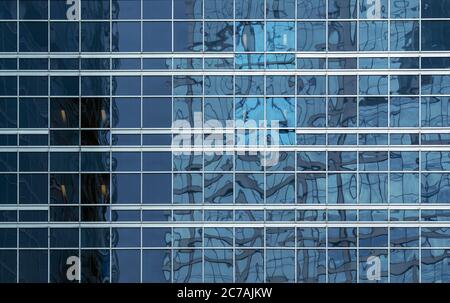 generic office building with glass facade reflecting sky and clouds ...