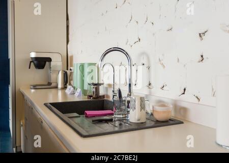 Kitchen interior with a metal faucet and different equipment hanging on ...