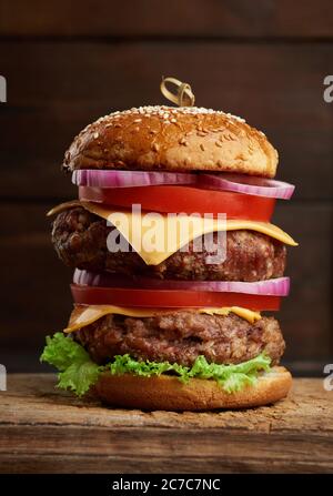 cheeseburger with tomatoes, onions, barbecue cutlet and sesame bun on ...