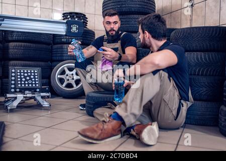 Mechanics resting after hard work, they changing tires on their job ...