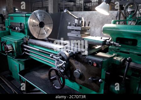 closeup of metallic lathe working against factory industrial interior ...