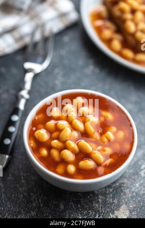 Cooked red kidney beans in a dark ceramic bowl on a rustic wooden table ...