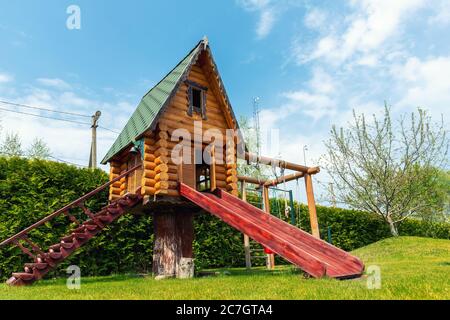 Small wood log playhouse hut with stairs ladder and wooden slide on ...