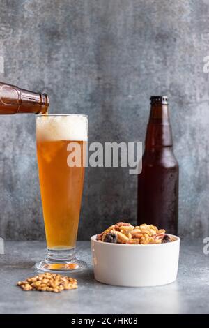 Pouring of beer from bottle in Spanish outdoor cafe and tapas bowl with ...