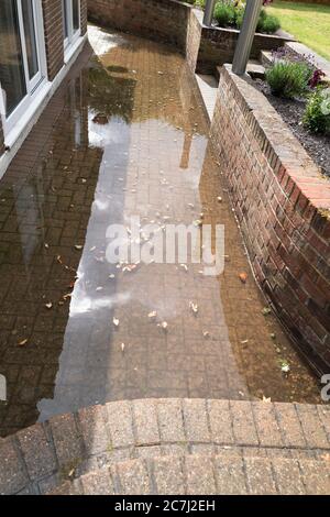 Brick patio area flooded after heavy rain due to a blocked soakaway ...