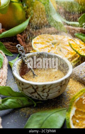 Closeup of tangerine powder in a bowl on a table surrounded by dry ...
