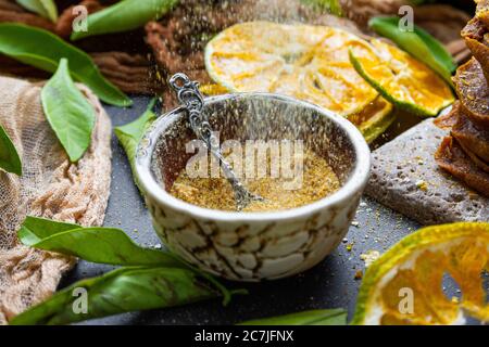 Closeup of tangerine powder in a bowl on a table surrounded by dry ...