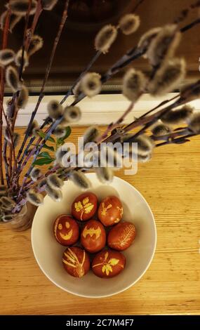 A high angle shot of a bowl of decorated eggs for Easter on a pink ...