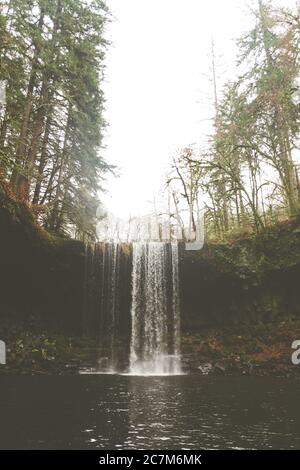 A low angle shot of a beautiful waterfall and the rainbow going through ...