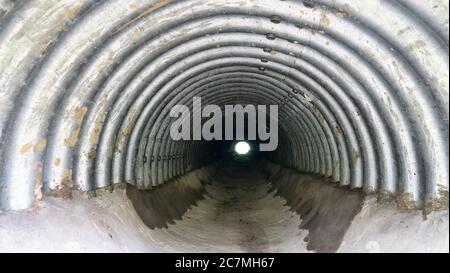 Drainage pipe under the highway (culvert). Filming inside the pipe ...