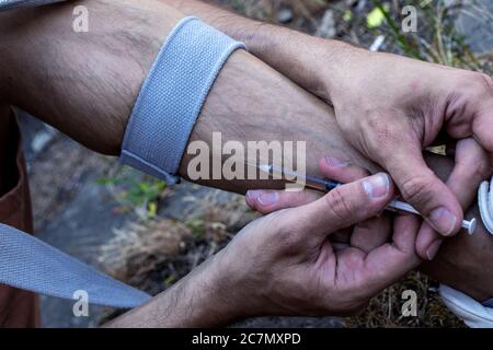 Hands of a drug addict with a syringe full of narcotic, heroin or ...