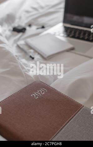 2020 calendar notebook along with a laptop, black wireless earbuds and ...