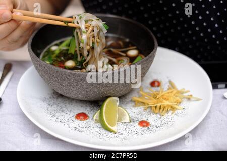 Man eating bowl of Phở Bò (beef pho) and Gà Da Dòn (crispy-skin chicken ...