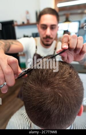 A vertical closeup shot of a male barber working with a duster after a ...