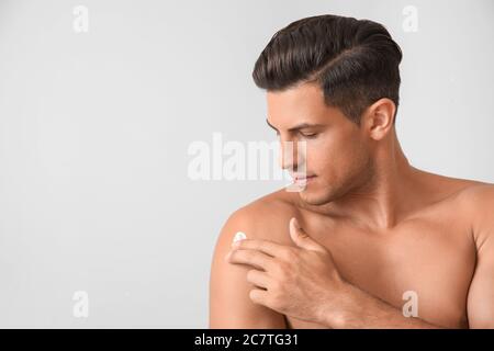 Young man applying sunscreen cream against color background. Banner for ...
