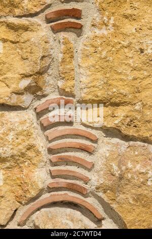 Close up of the façade of a brick wall with weathered yellow paint and ...