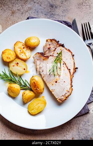 Grilled pork with baked golden potatoes served with red sauce on a dark ...