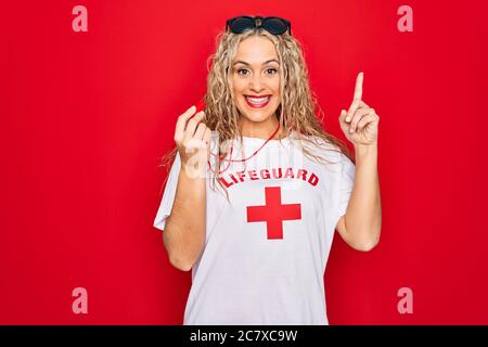 Young beautiful blonde lifeguard woman wearing t-shirt with red cross ...