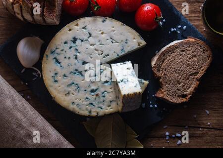 Round blue cheese surrounded by bread, tomatoes and garlic Stock Photo ...