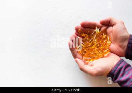 Man holds fish oil capsule close to mouth while looking at jar Stock ...