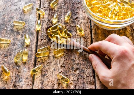 Man holds fish oil capsule close to mouth while looking at jar Stock ...