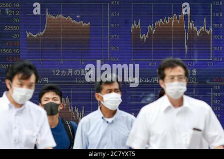 Tokyo, Japan. 20th July, 2020. Pedestrians walk past an electronic ...