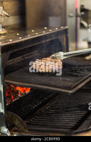 Stylish master chief male with tattoo on his arm grilling a beef in a ...