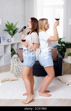Full length of two beautiful drunk women drinking champagne and ...