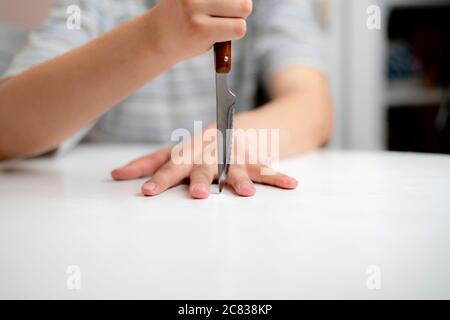 hand with knife hitting between the fingers on the table, playing the ...