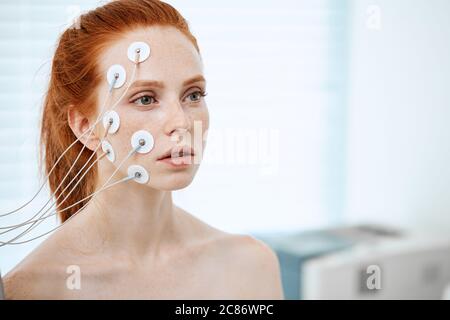 Female patient wearing electrodes on her chest, connected to a Holter ...
