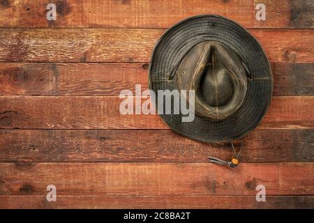 weathered outback oilskin hat hanging on rustic barn wooden wall, copy ...