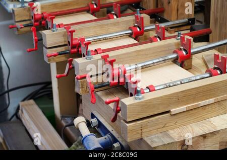 Red joiner's clamps are fixed on product, gluing of boards. Bonding of ...