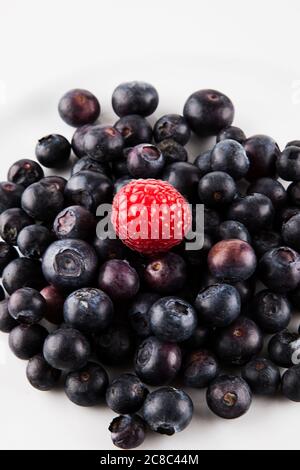 Odd one out raspberry on blueberries Stock Photo - Alamy