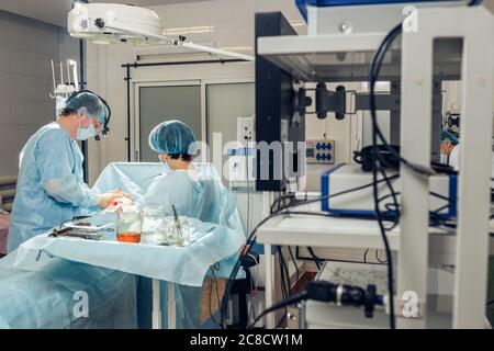 Wide view of a team of four surgeons operating on a patient in a dark ...