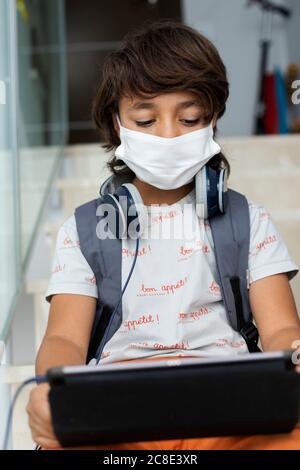 Caucasian schoolboy using tablet and headphones displayed on laptop ...