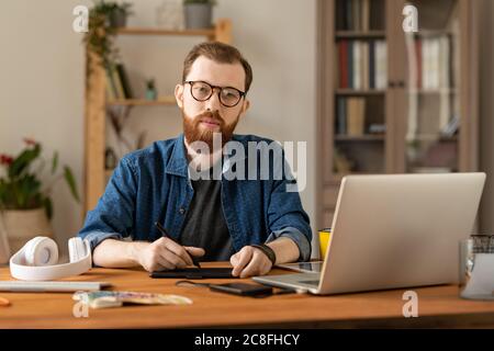 Young male illustrator using laptop in creative office Stock Photo - Alamy