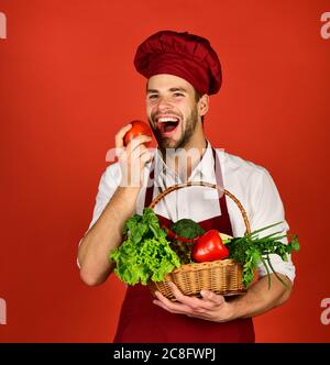 Chef in burgundy uniform eats cucumber. Vegetarian cuisine concept. Man ...