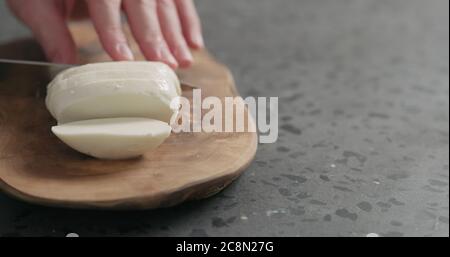man slicing fresh mozzarella cheese on olive wood board, wide photo ...