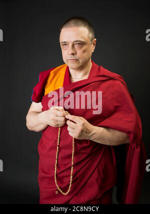 A Tibetan Buddhist in traditional outfit performing Dance with a Damaru ...