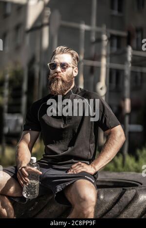 tired sportsman with bottle sitting on city bench Stock Photo - Alamy