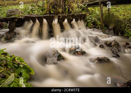 Traditional natural wash machine (valtoare) under a stream of water in ...