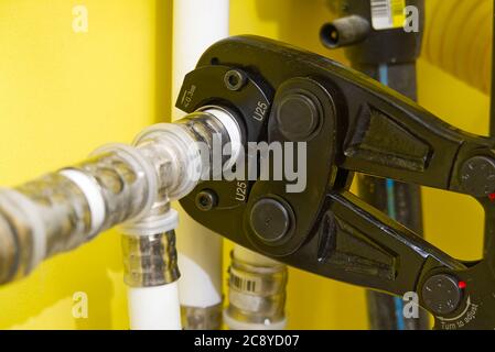 Worker connecting alupex pipes with a tap. Hand press for water pipes ...