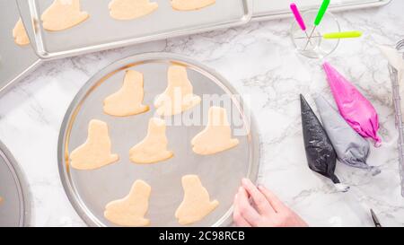 Flat lay. Decorating ice skate shaped sugar cookies with black color ...