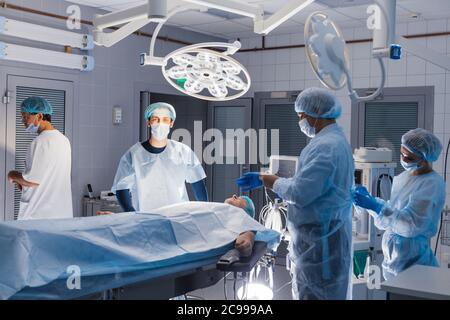 Medical assistant helping a surgeon put on sterile clothes in an ...