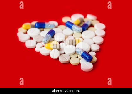 Heap of colorful pills in the shape of a heart, tablets and capsules on ...
