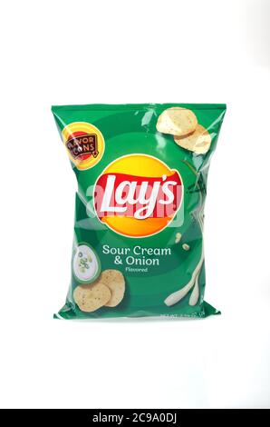 Snack food of potato crisps with sour cream and chive dip on white wood ...