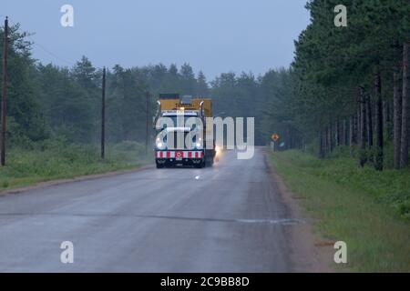 transport carrying a backhoe driving down the road Stock Photo - Alamy