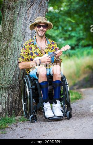 Young male artist in wheelchair painting picture against color ...